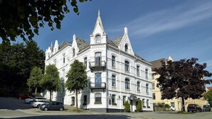 Um edifício histórico branco com vários andares, detalhes arquitetônicos ornamentados e uma torre imponente.