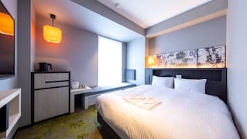 Quarto de hotel moderno com uma cama grande, uma escrivaninha com cadeira, um pequeno espaço de estar e uma janela ampla.