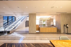 Um lobby de hotel moderno com um balcão de recepção, um balcão de madeira e um escadutor.