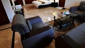 Uma sala de estar ampla com um grande sofá, uma mesa de centro e uma cama com mesa de cabeceira.
