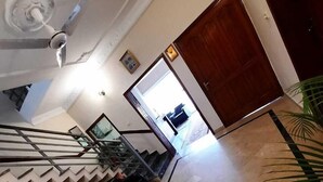 Um corredor amplo com piso de mármore, escada e ventilador de teto.