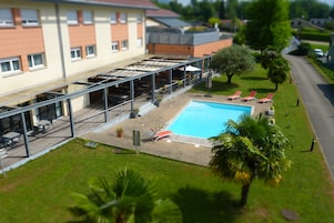 Um hotel com piscina, área de estar ao ar livre e um pátio coberto.