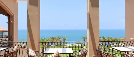 Varanda com mesa e cadeiras, vista para o oceano.
