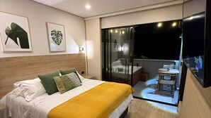 Um quarto moderno com uma cama grande, uma varanda com porta de vidro e obras de arte nas paredes.