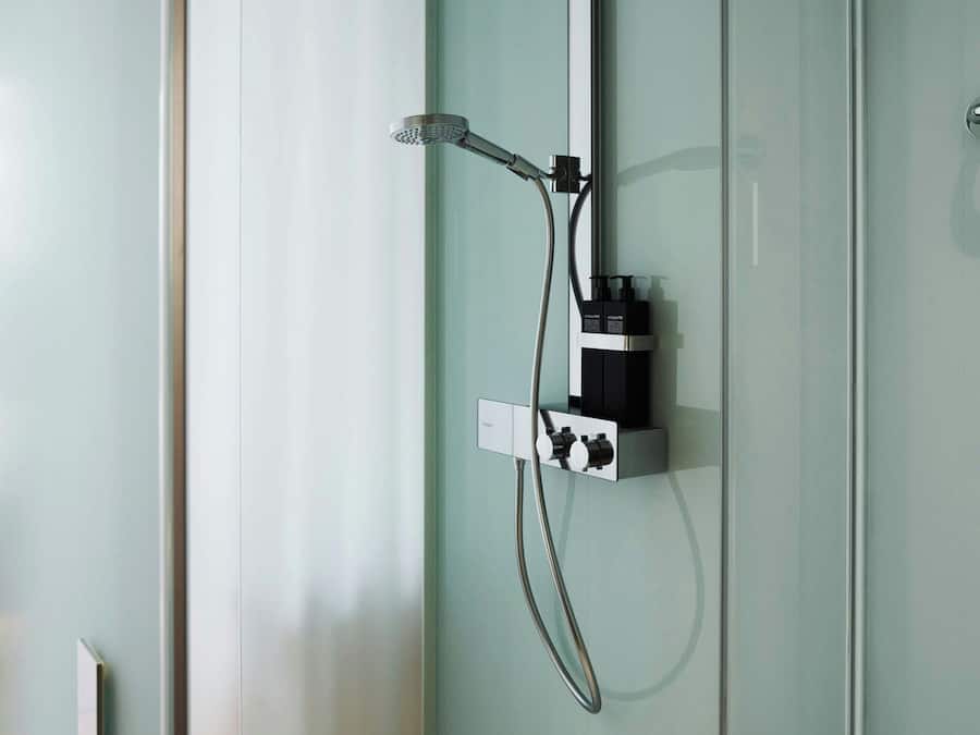 Um chuveiro moderno com um chuveiro manual e um painel de controle fixado na parede.