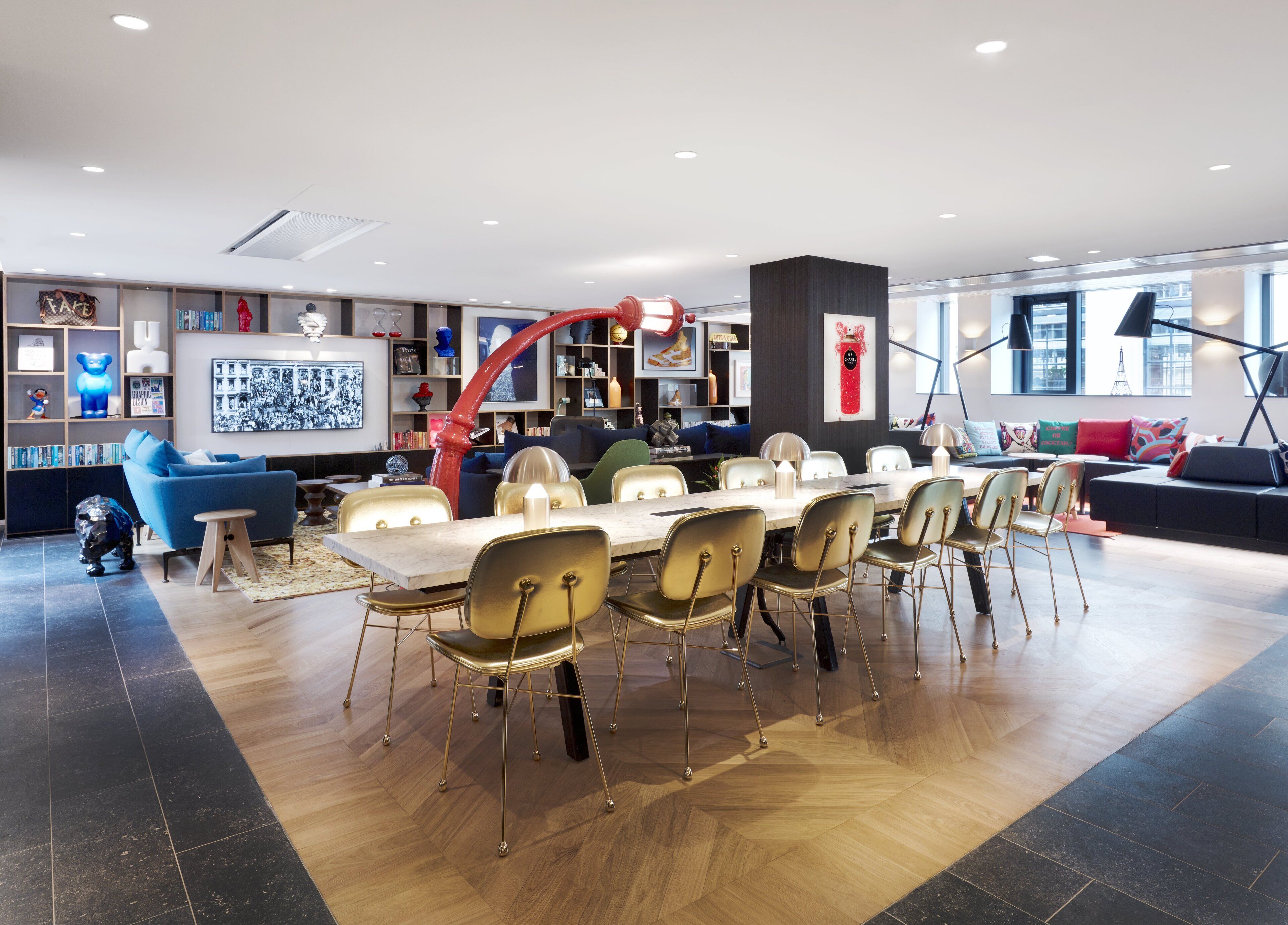 Uma área de jantar moderna com uma mesa comprida, várias cadeiras e uma escultura vermelha central.