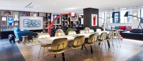 Uma área de jantar moderna com uma mesa comprida, várias cadeiras e uma escultura vermelha central.