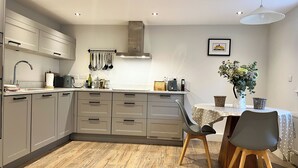 Uma cozinha moderna com armários cinza, piso de madeira e um espaço de refeições com mesa e cadeiras.
