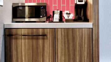 Cozinha com micro-ondas, cafeteira e painel de azulejos vermelhos.