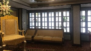 Um quarto com uma janela grande, um sofá, uma cadeira e um vaso decorativo.