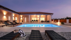 Uma área de piscina com espreguiçadeiras e um espaço de refeições com mesas e cadeiras.
