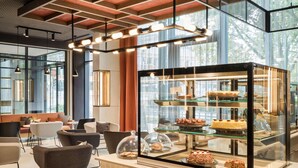 Um café moderno com uma vitrine de doces, assentos confortáveis e grandes janelas.