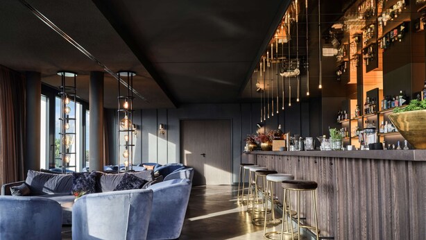 Uma área de bar moderna com balcão, banquetes e assentos.