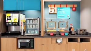 Balcão de café da manhã com máquina de café, máquina de venda automática e torradeira.