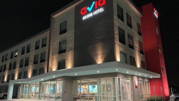 Um hotel moderno com um letreiro 'avid' em destaque, janelas amplas e uma entrada bem iluminada.