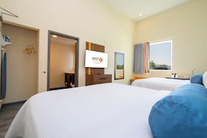 Quarto de hotel com duas camas, televisão, espelho e janela com cortinas.