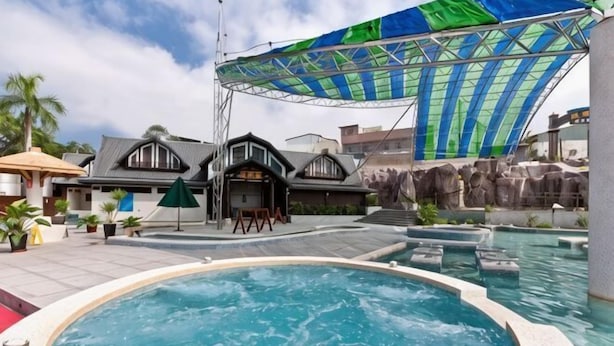 Piscina com hidromassagem, área de estar coberta e cascata.