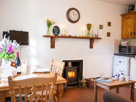 Uma sala de estar aconchegante com lareira, móveis de madeira, um relógio e uma área de cozinha com eletrodomésticos.