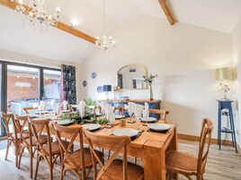 Uma sala de jantar com mobiliário de madeira, um lustre e vista para o exterior.