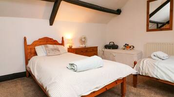 Quarto com cama de madeira, mesa de cabeceira com abajur, cômoda e espelho na parede.