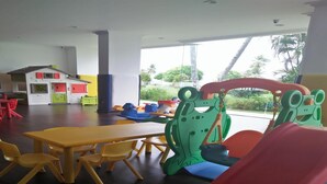 Uma área de recreação infantil com escorrega, mesas, cadeiras e um casinha.