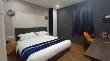 Quarto de hotel com cama, escrivaninha, cadeira e janela com cortinas.