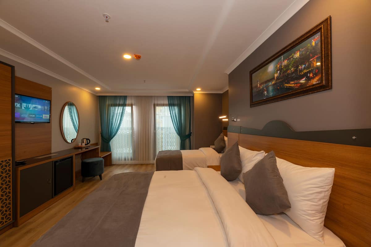 Quarto de hotel com uma cama grande, uma escrivaninha, uma televisão e um quadro na parede.