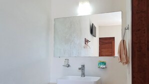 Casa de banho com uma pia branca, espelho e toucador de madeira.