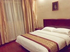 Quarto de hotel com cama, cortinas, mesa de cabeceira e um quadro na parede.