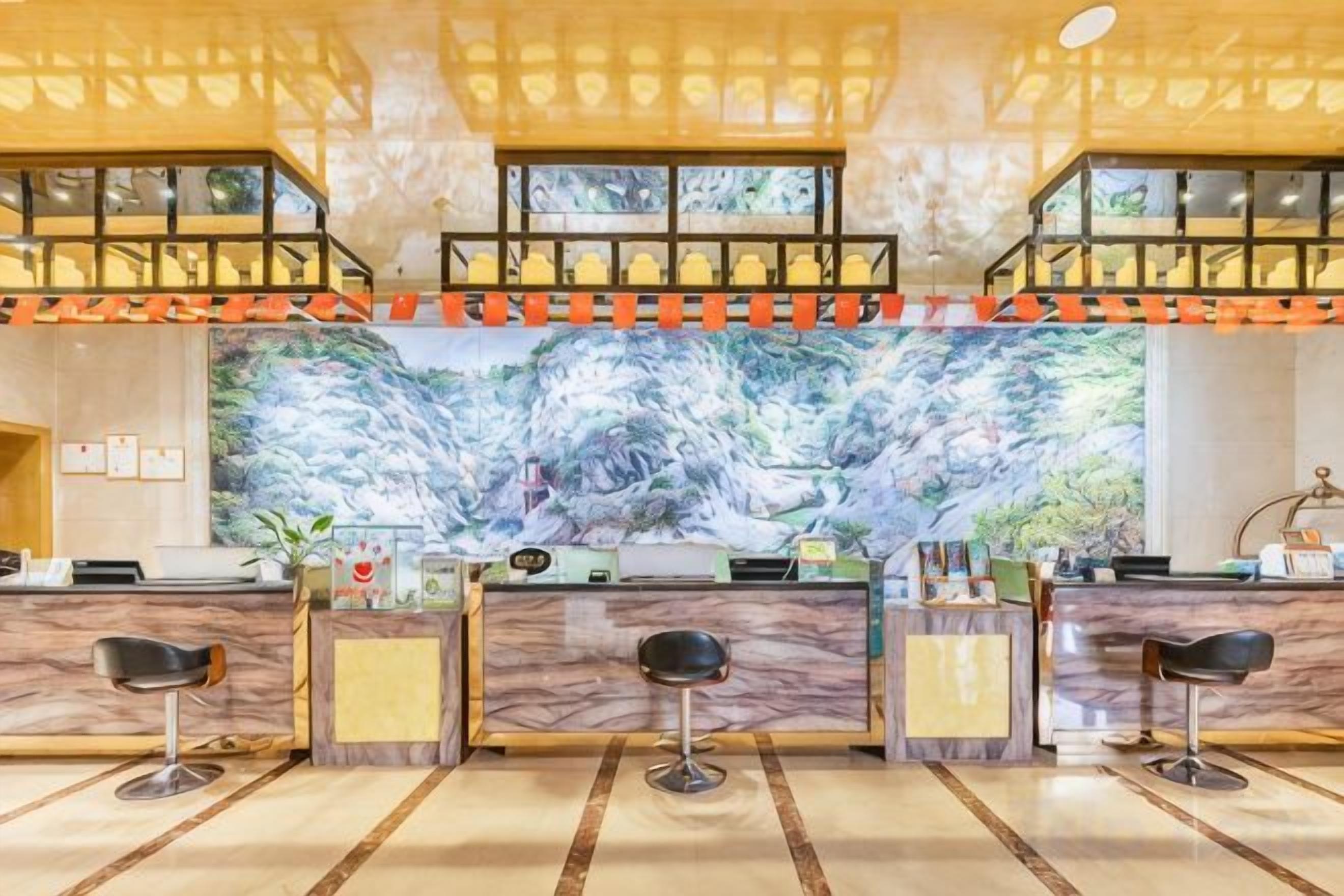 Uma área de recepção com um grande mural, um balcão e três banquetas.