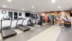 Uma academia com esteiras, elípticos e uma bicicleta ergométrica.