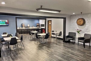 Um saguão de hotel moderno com cozinha, mesas de jantar e cadeiras.