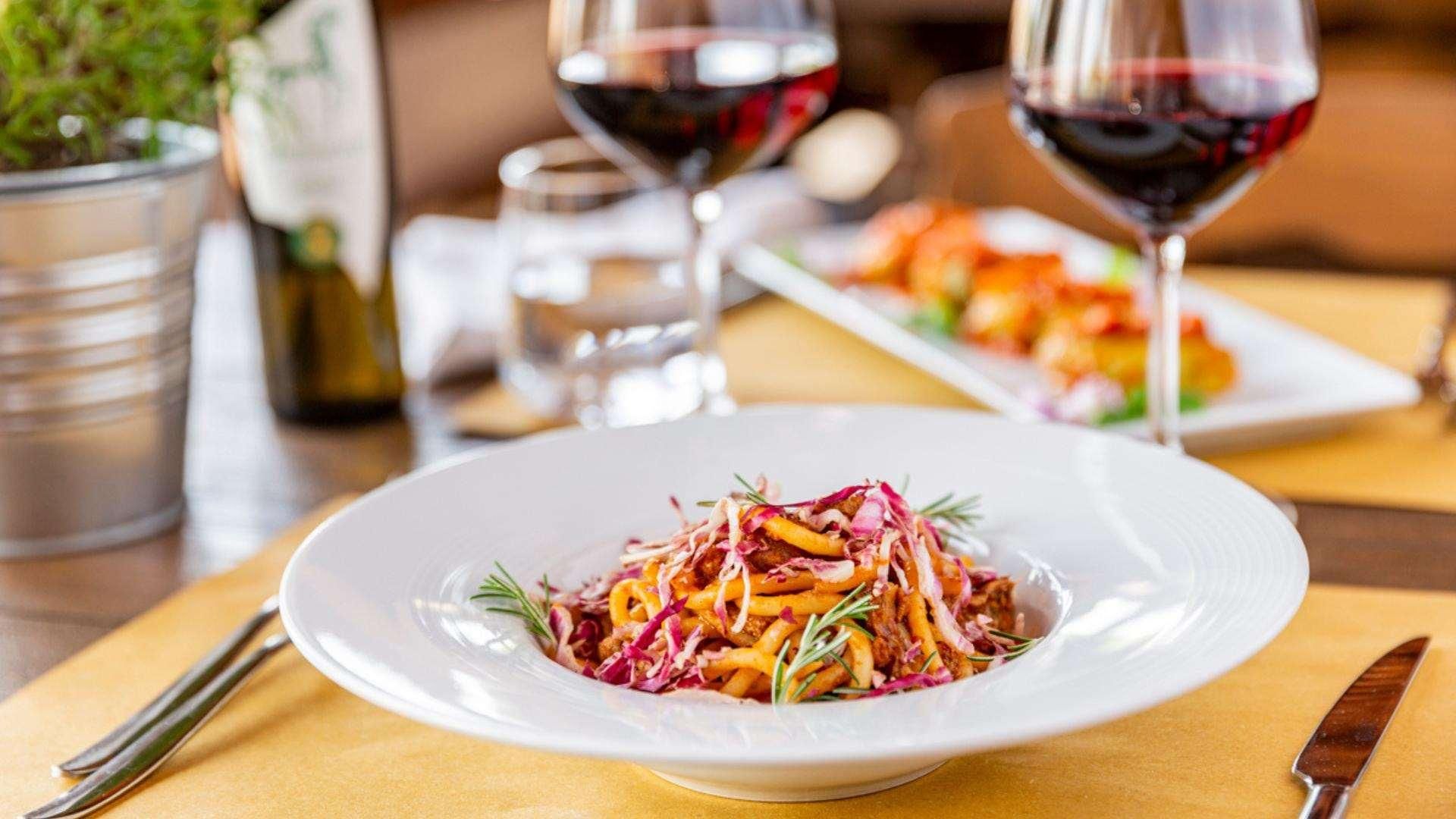 Prato de comida com um copo de vinho tinto e um copo de água sobre a mesa.