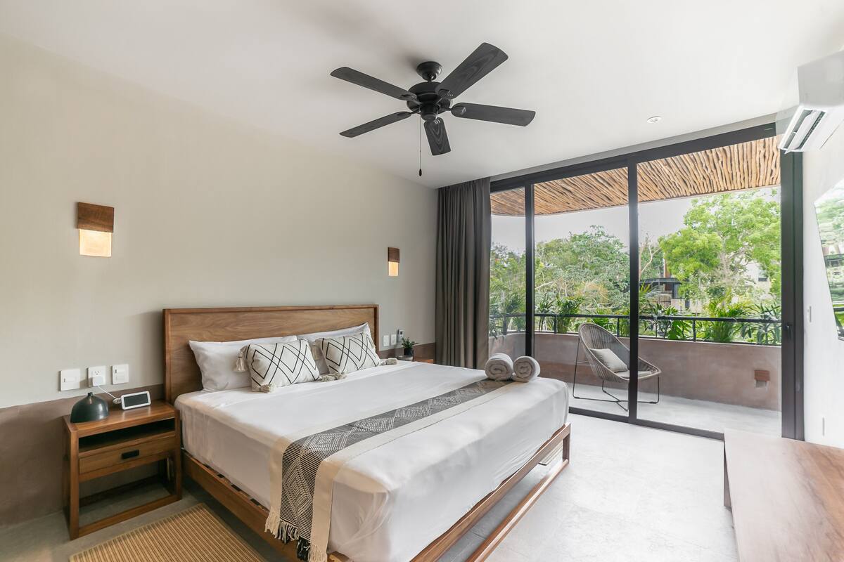 Quarto com cama, mesa de cabeceira e ventilador de teto.