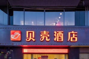 Placa de hotel com caracteres chineses iluminados e um logotipo.
