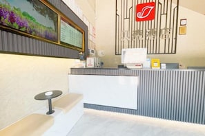 Uma área de recepção com design moderno, com balcão de atendimento, espaço de estar e um painel fixado na parede.