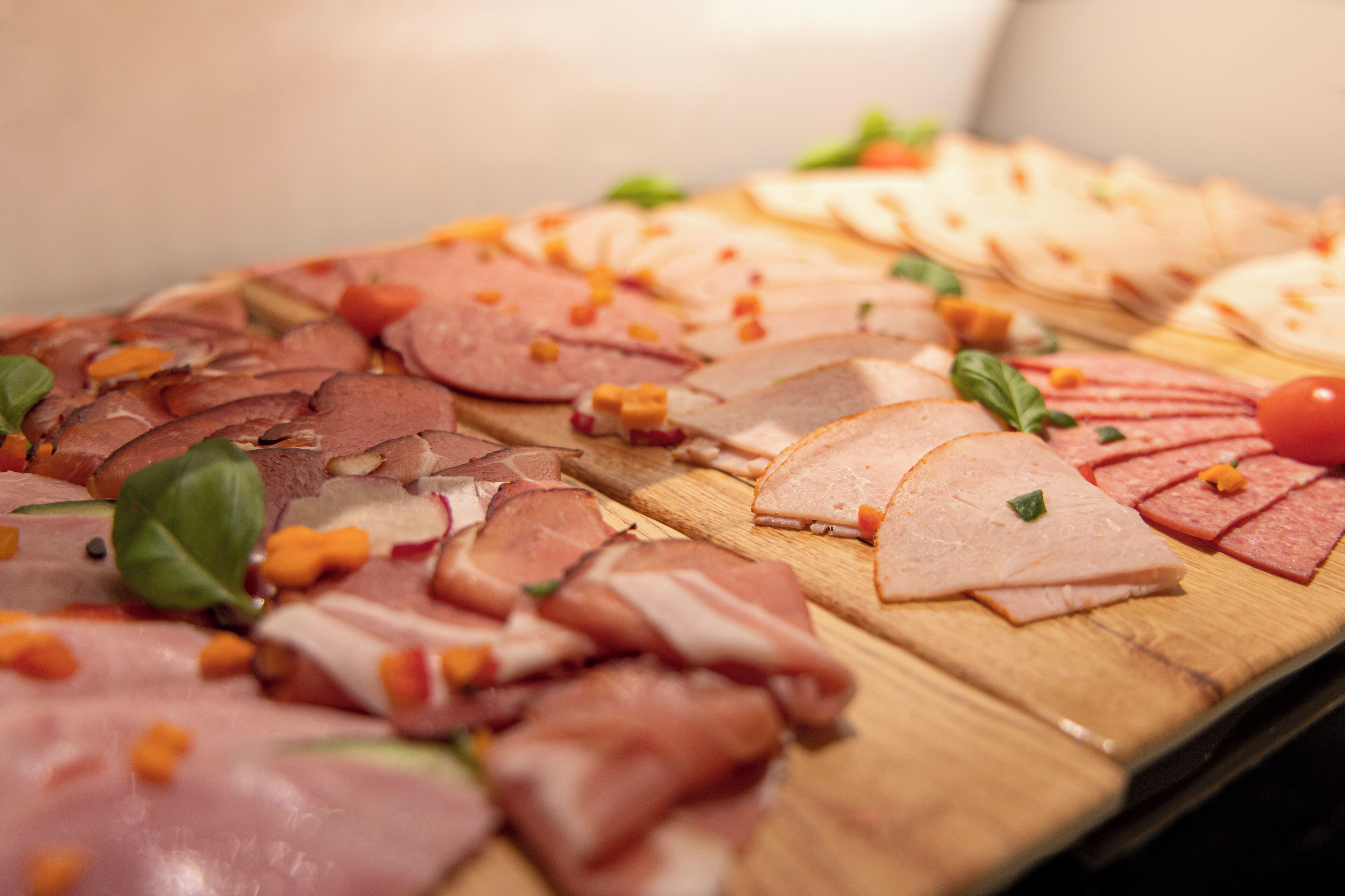 Uma tábua de madeira com diversos tipos de carne fatiada e acompanhamentos.