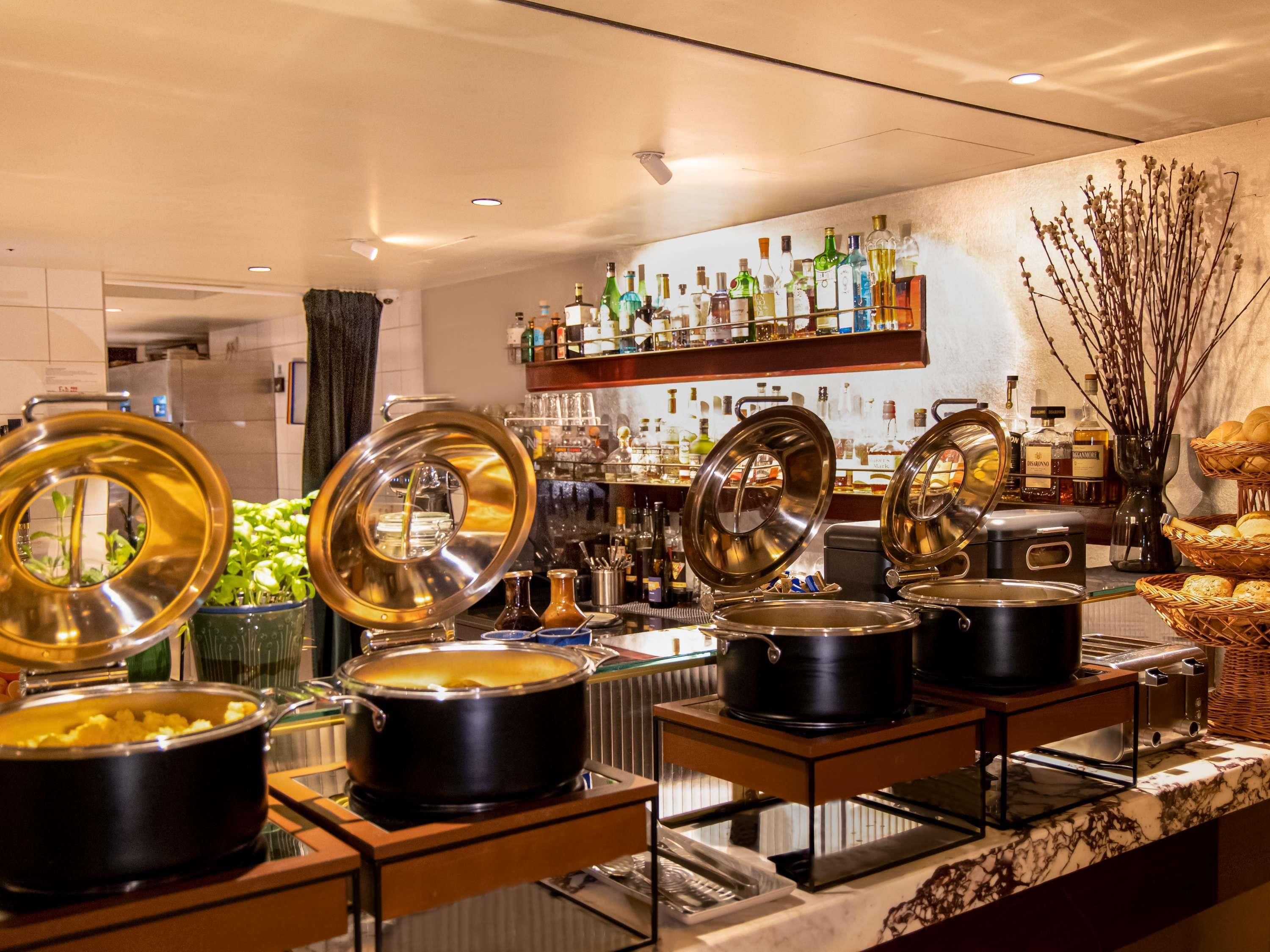 Uma área de buffet com vários pontos de serviço, cada um com uma panela grande e uma tampa.