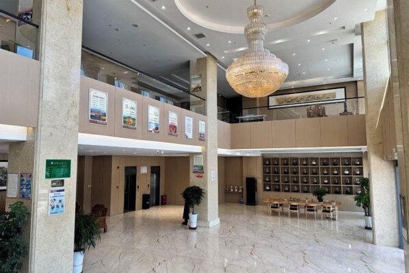 Um hall amplo com teto alto, um candelabro e um espaço de estar.