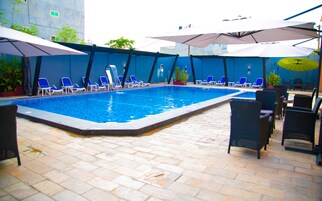 Uma piscina com água azul, rodeada por espreguiçadeiras e guarda-sóis azuis.