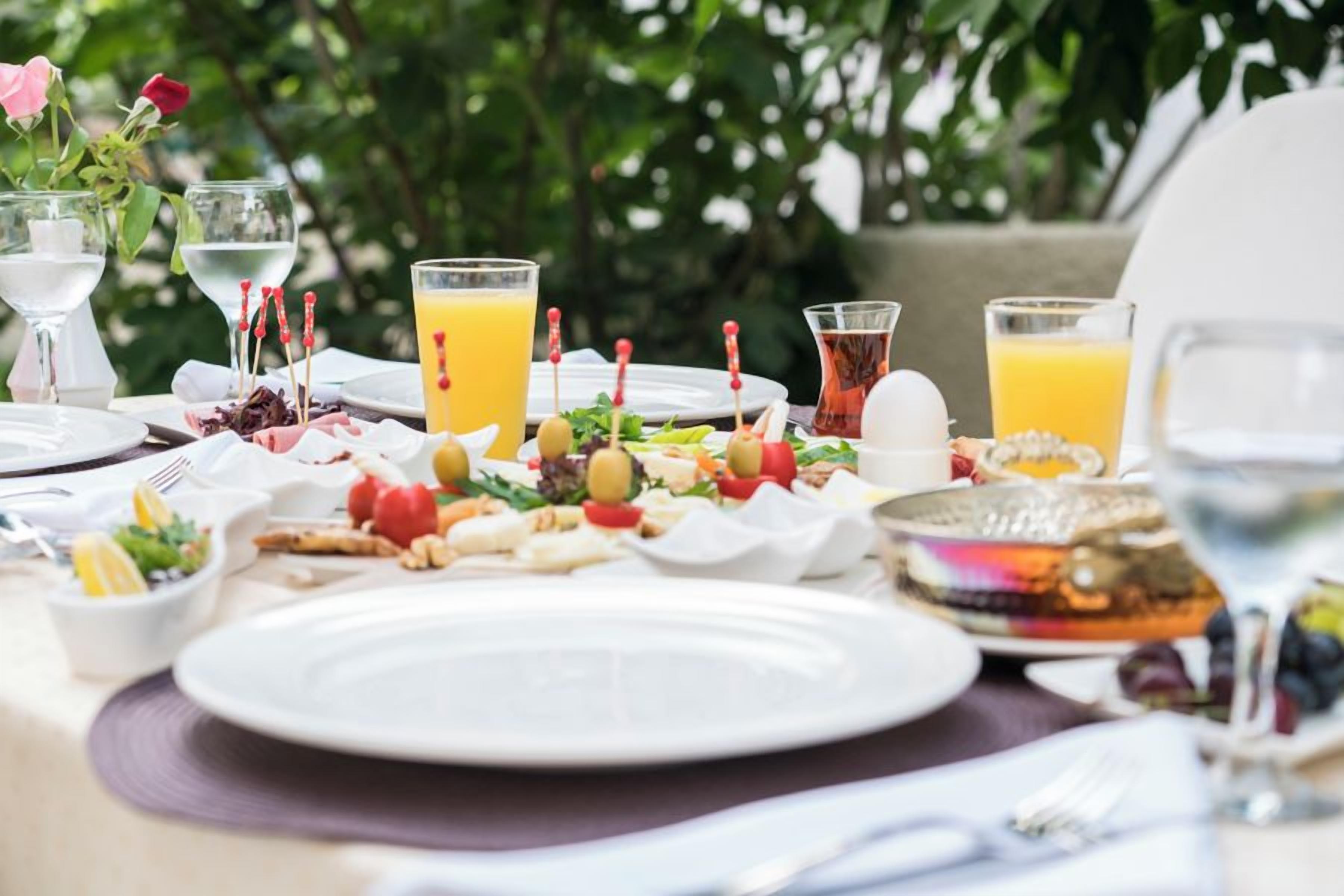 Mesa posta para refeição com diversos pratos, copos de suco de laranja e um copo de água.