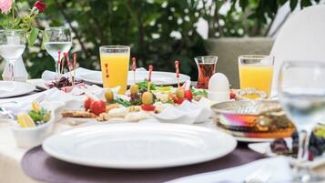 Mesa posta para refeição com diversos pratos, copos de suco de laranja e um copo de água.
