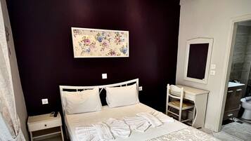 Quarto de hotel bem organizado, com uma cama grande, mesa de cabeceira, cadeira, escrivaninha e espelho.