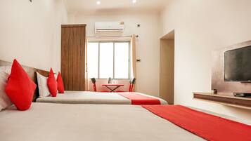 Quarto de hotel com cama, almofadas vermelhas, televisão e janela.