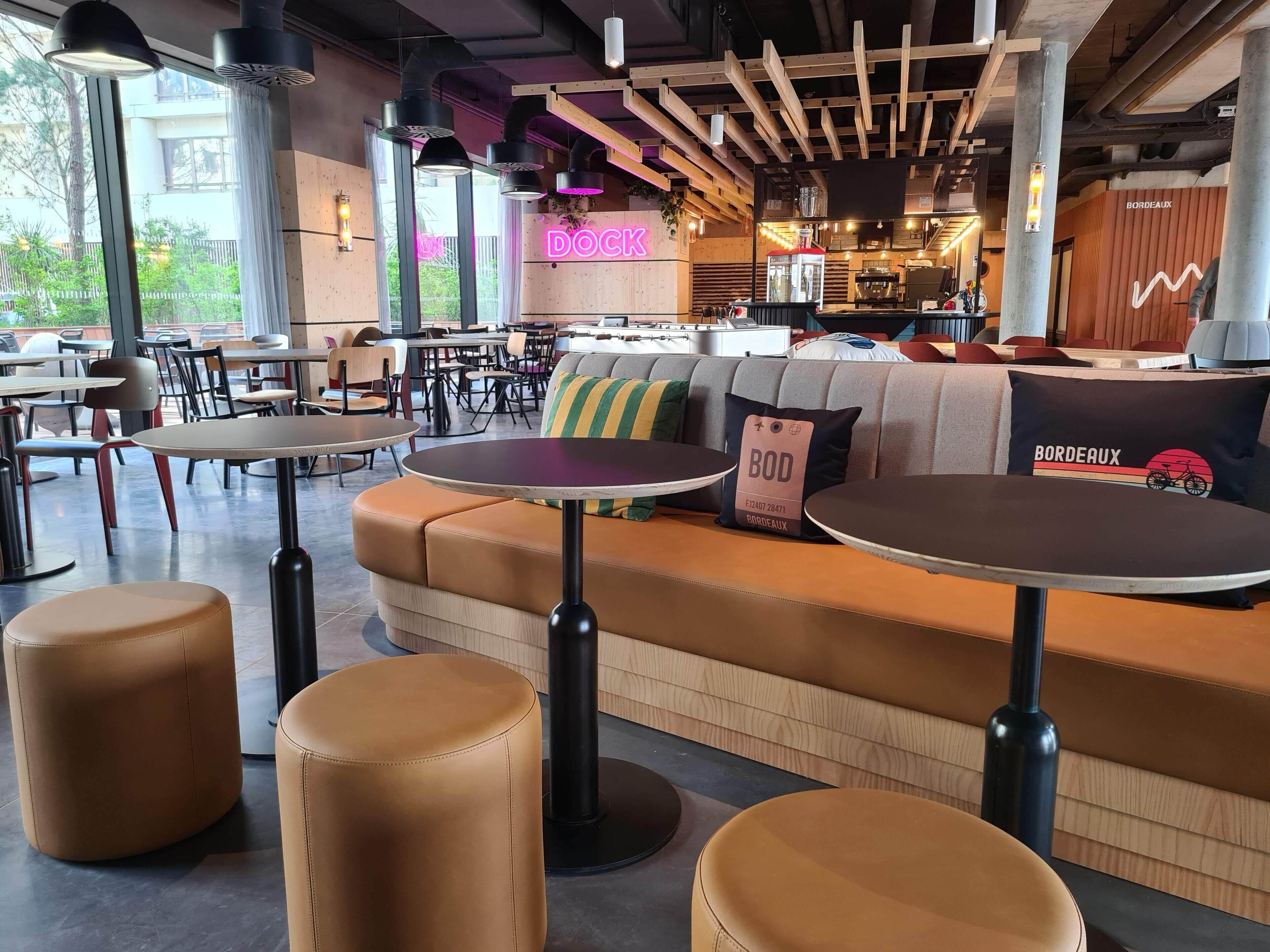 Um café moderno com assentos de couro, mesas e um letreiro de neon.