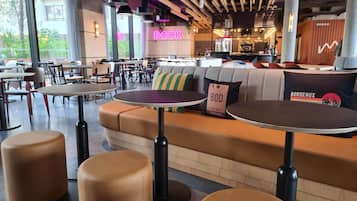 Um café moderno com assentos de couro, mesas e um letreiro de neon.