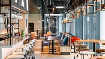 Uma área de bar moderna com banquetas altas, balcão e um espaço de estar com bancos estofados.