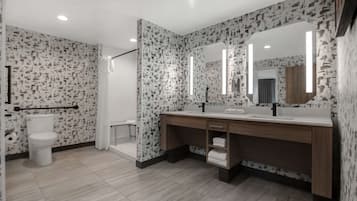 Casa de banho moderna com papel de parede estampado, sanita, chuveiro e toucador com espelho.