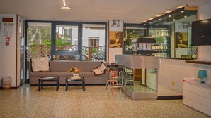 Uma sala de estar com sofá, mesa de centro e um pequeno espaço bar com banquetas.