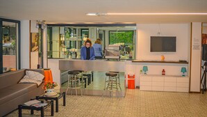 Um interior moderno com sofá, banquetas de bar, televisão e área de cozinha.